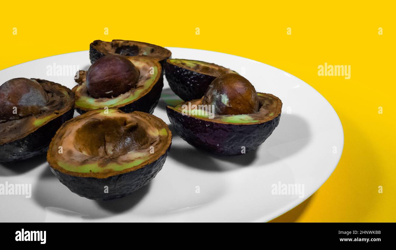 Plate Contaminated Tropical fruits. Bad Avocado Half Close up on Yellow ...
