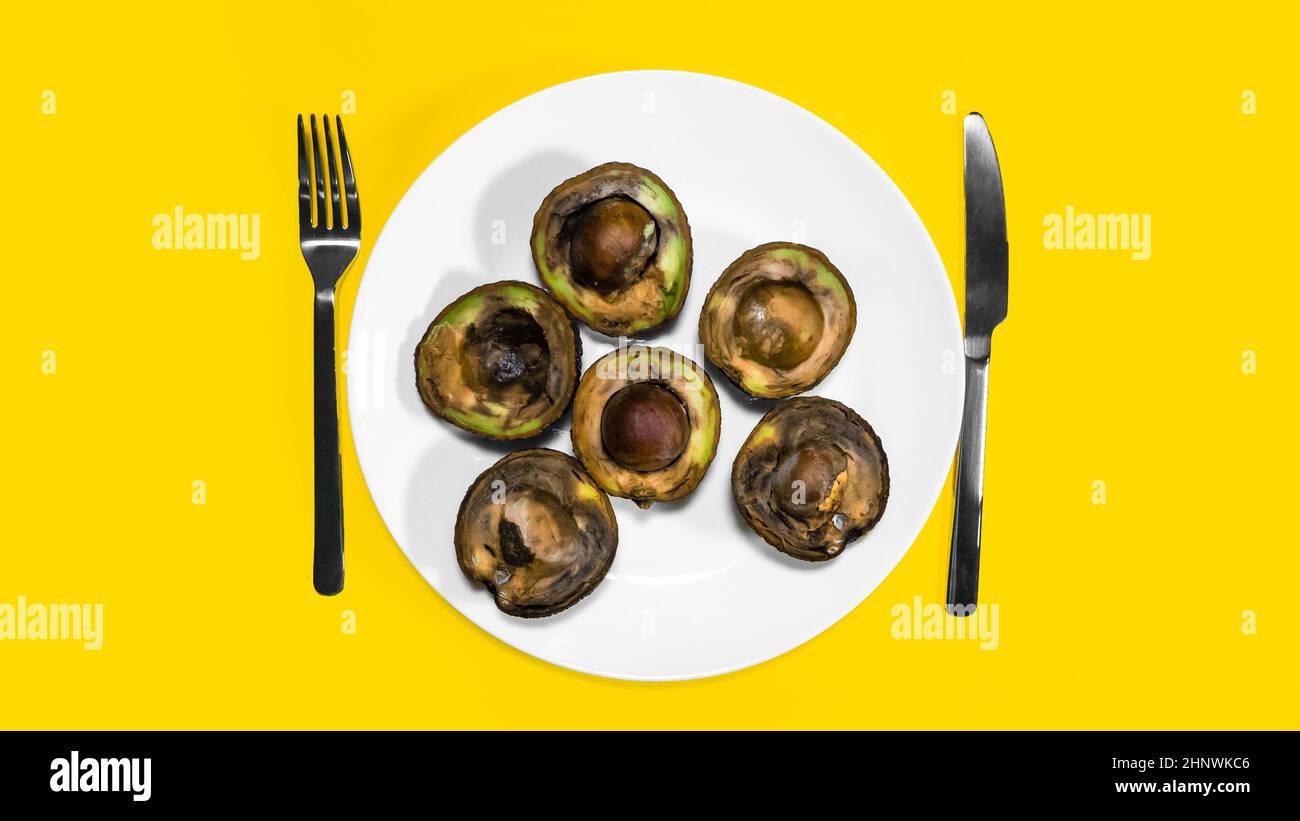 Bad Avocado halfs placed on plate with fork and knife Yellow background ...