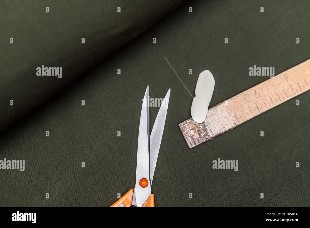 tailor marks up textile using soap and wooden ruler on pattern cutting ...