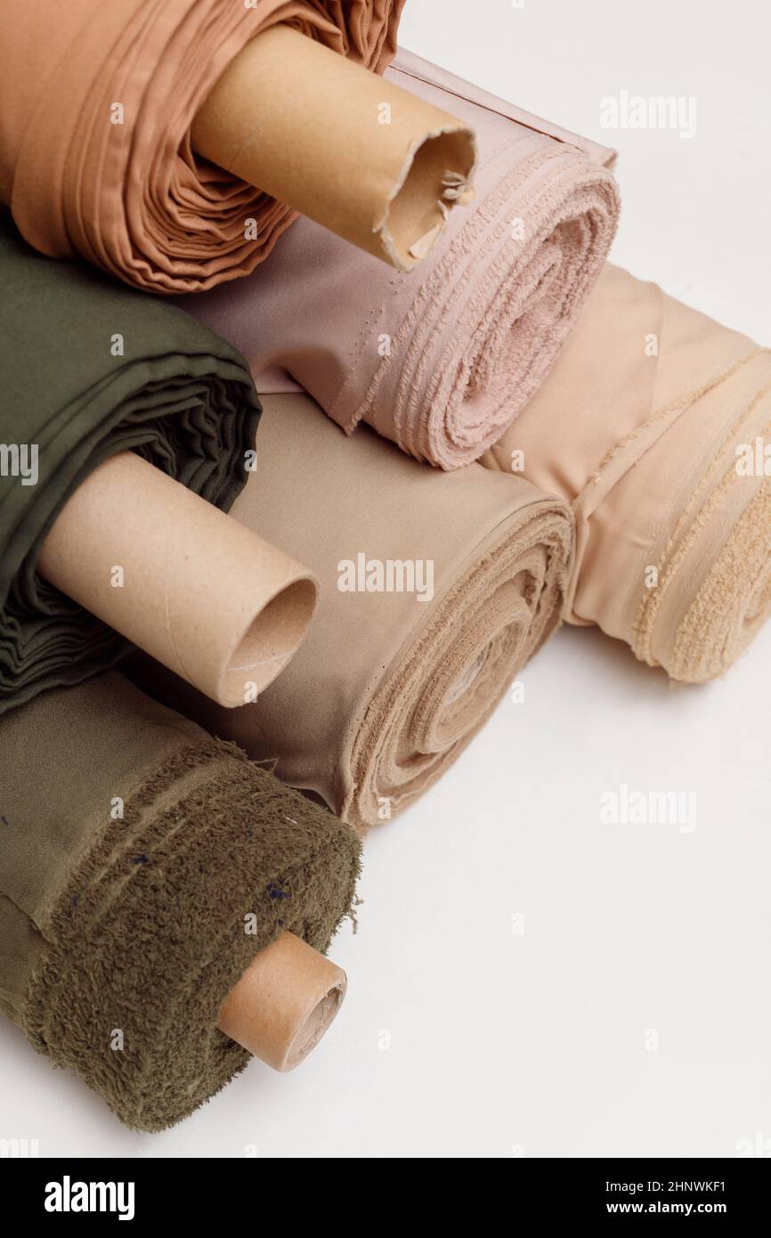 Stack of pastel color fabric rolls of synthetic and natural fabrics ...