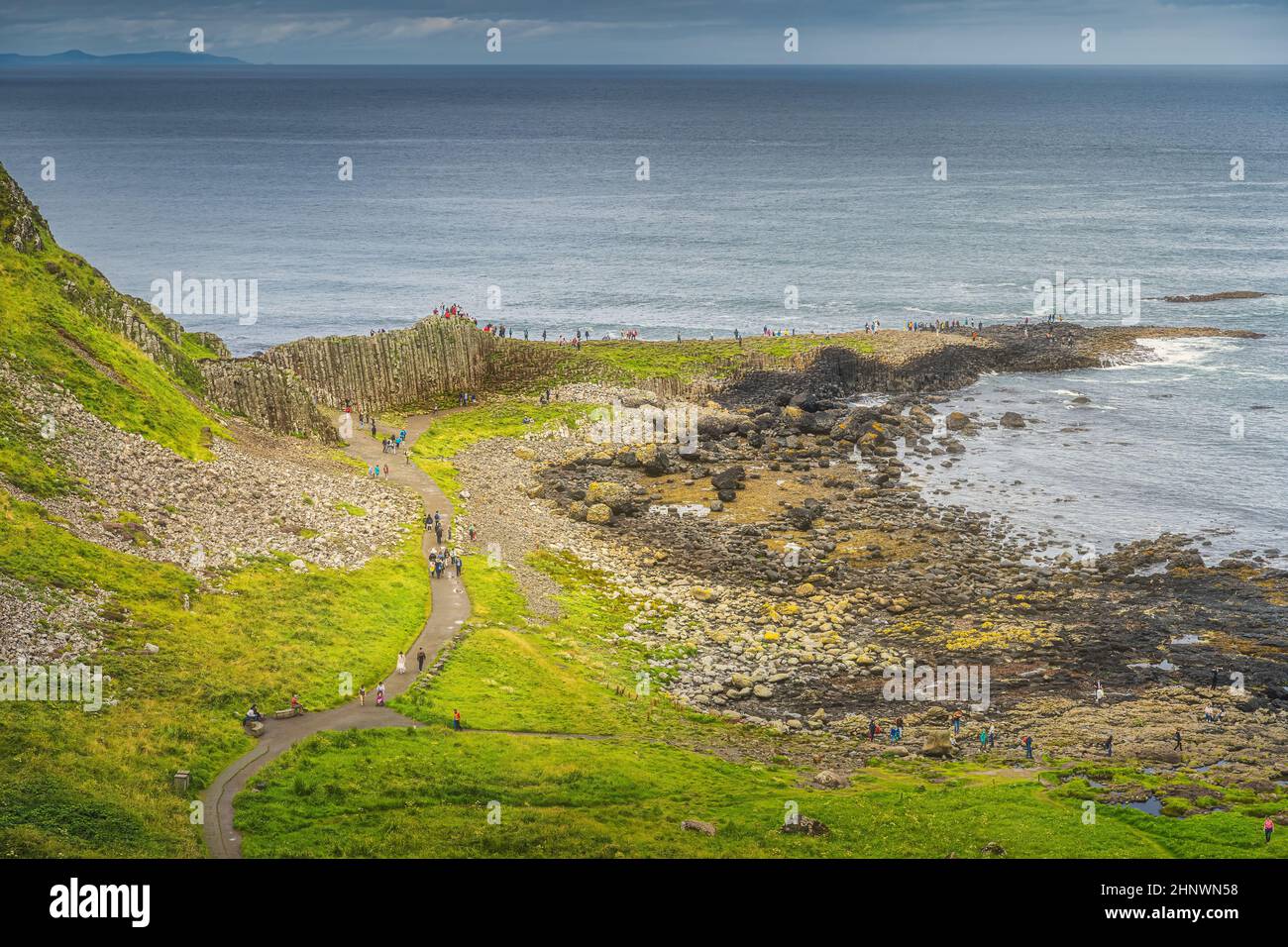 Tourists on main hexagonal rock formation in Giants Causeway seen from ...