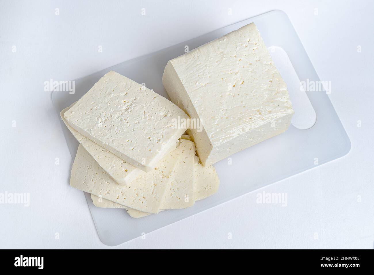 White cheese cut into several pieces on a white surface and white ...