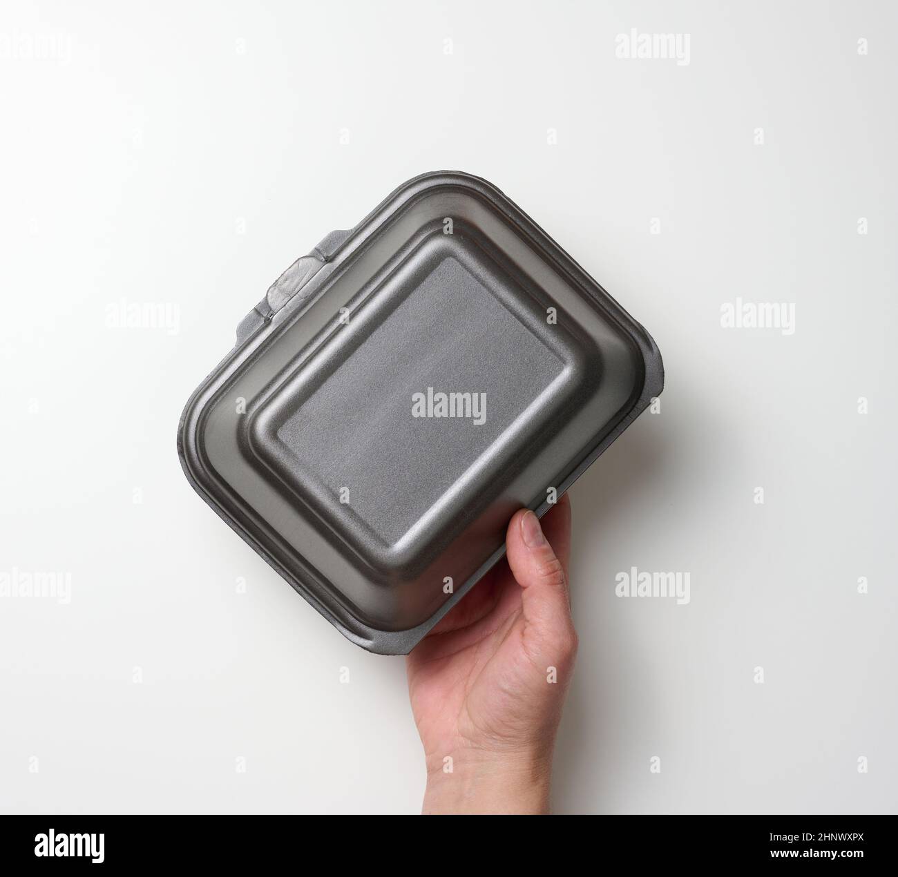 female hand holds a disposable food container. Gray box of polystyrene ...
