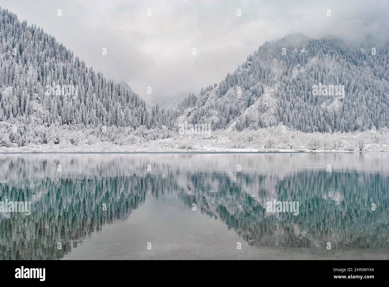 Mountain lake in winter. Snow-covered mountains are reflected in the ...