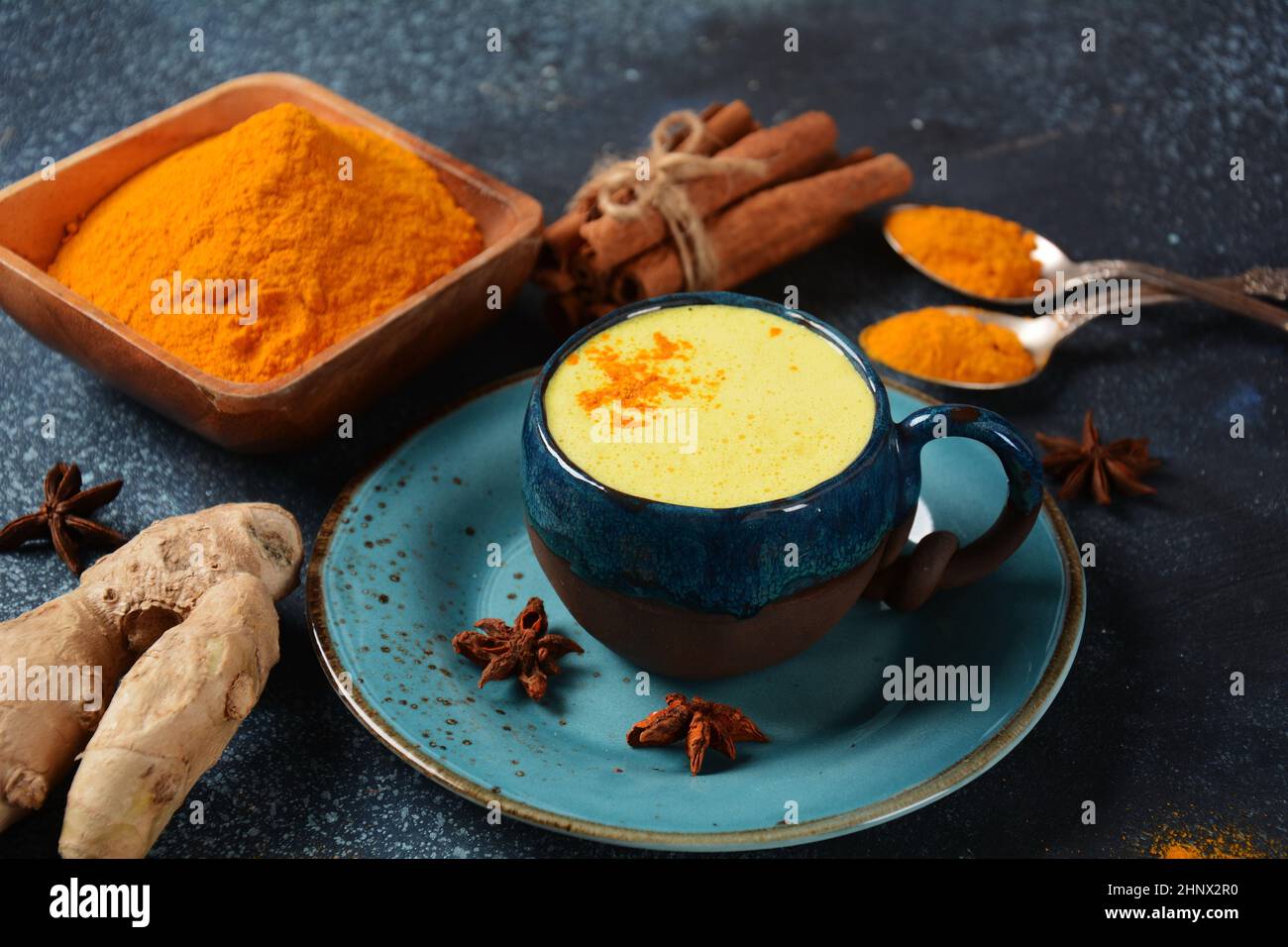 Tasty hot turmeric curcuma milk in cup on table. Arranged with turmeric ...