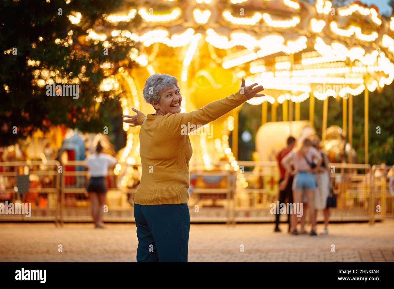 Pretty granny poses in summer amusement park, bright illumination on ...