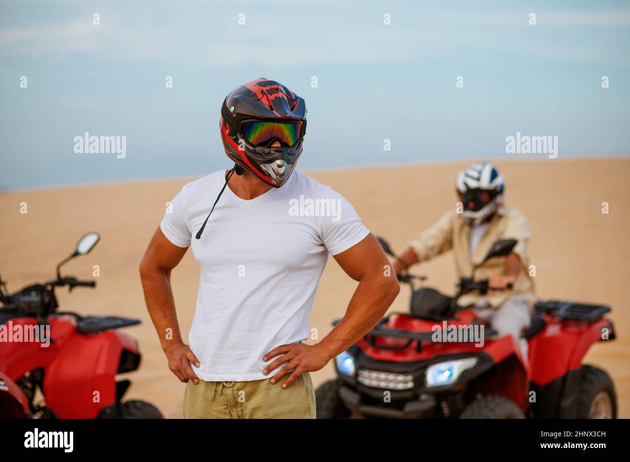 Two racers in helmets poses near atvs, freedom riding in desert. Male ...
