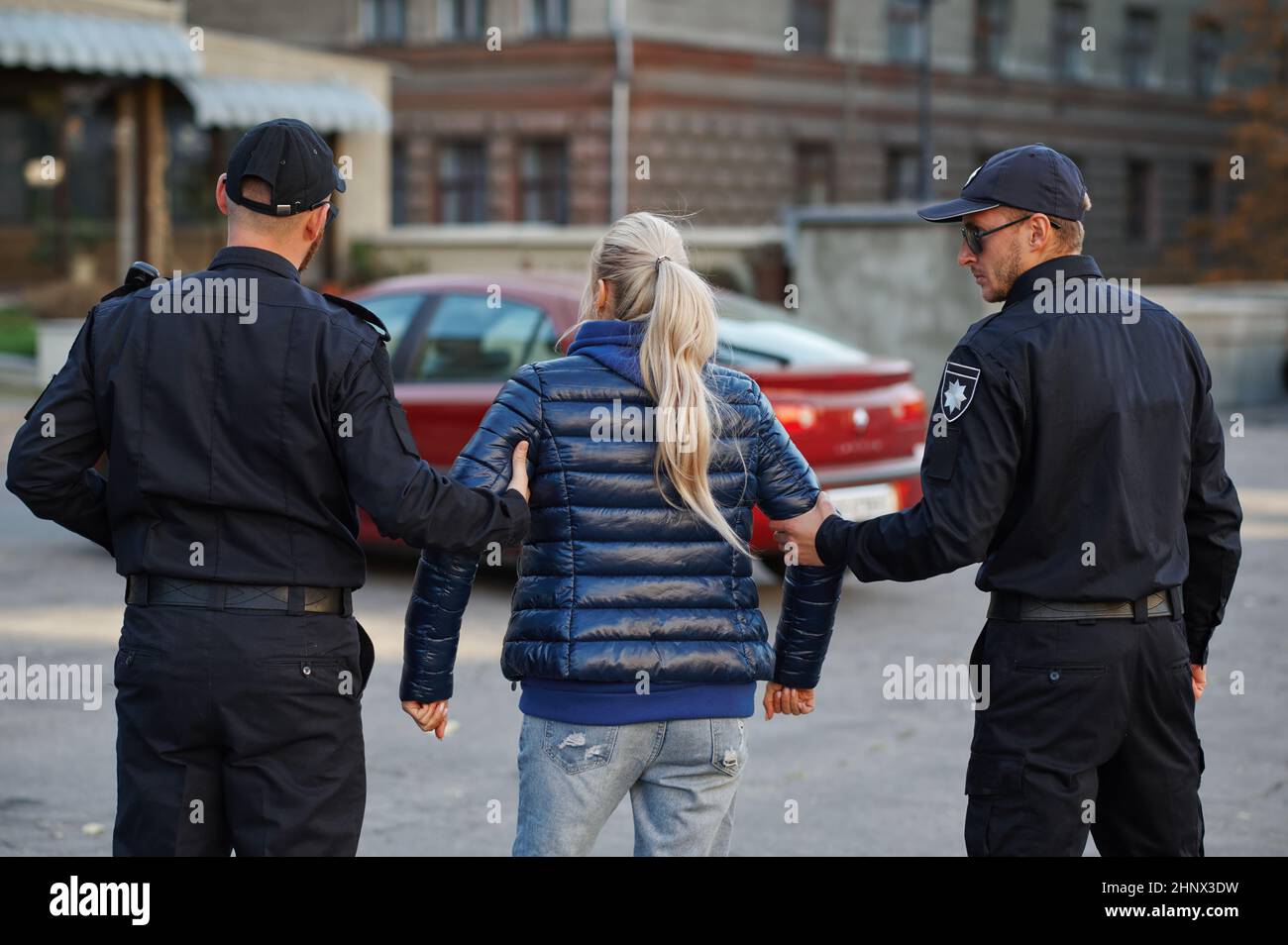 Two male police officers arrest young woman. Policemen in uniform ...