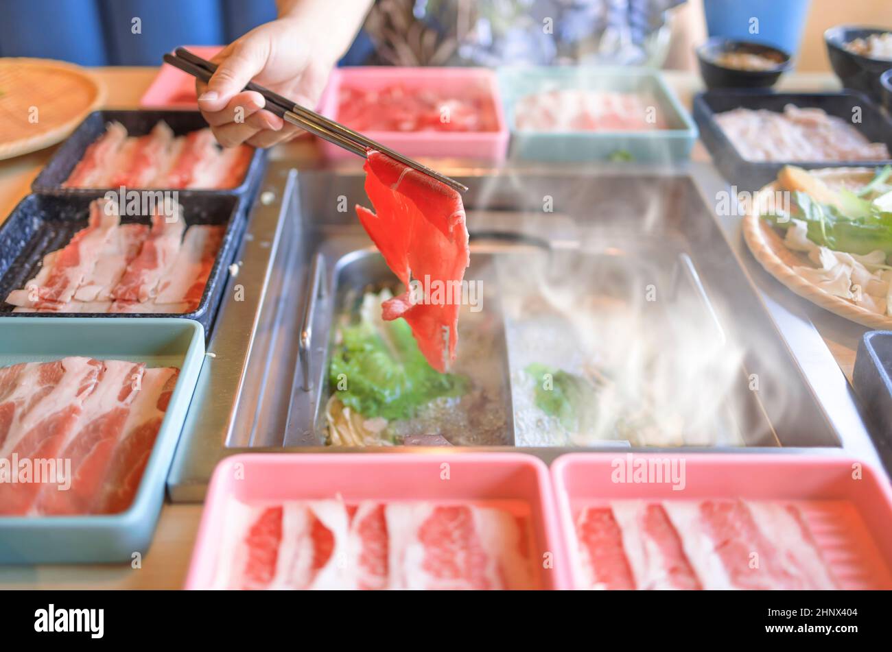 Chinese hot pot meal. Hands taking food with chopsticks Stock Photo - Alamy