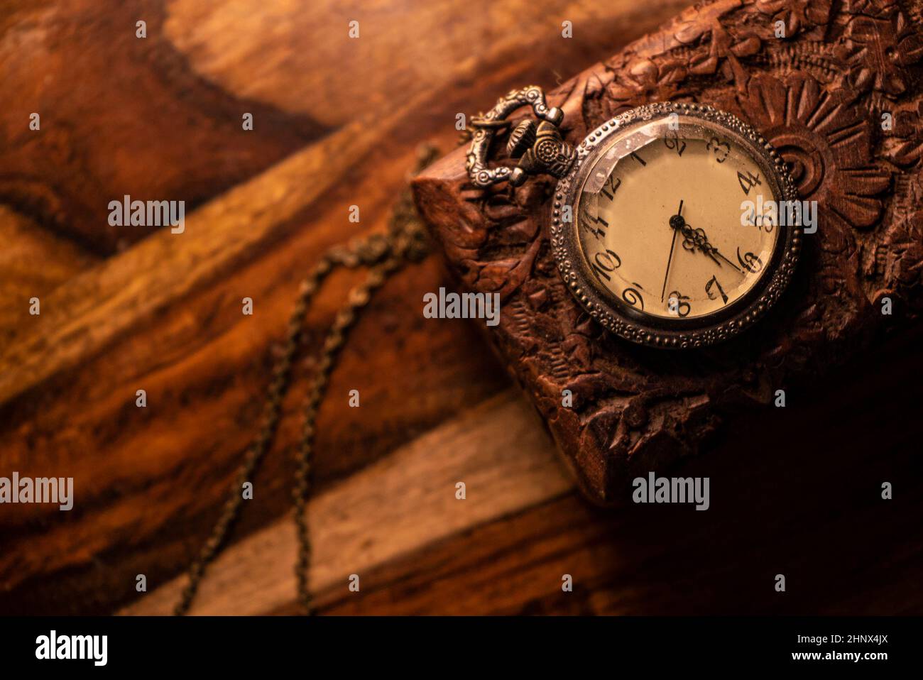On the table are an old pocket watch over an ancient wooden case ...