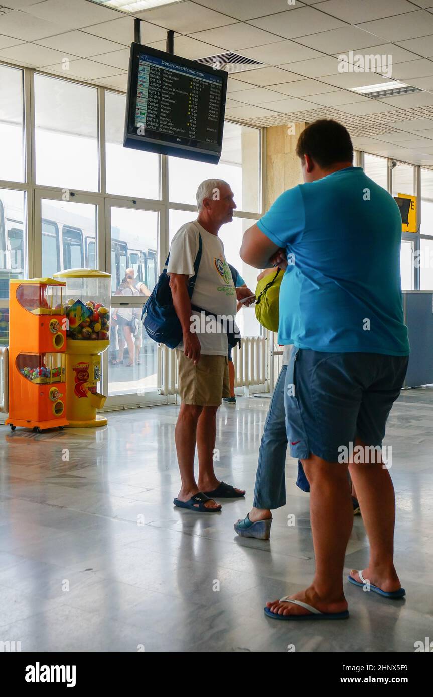 Vertical shot of people waiting next to a screen with departure ...