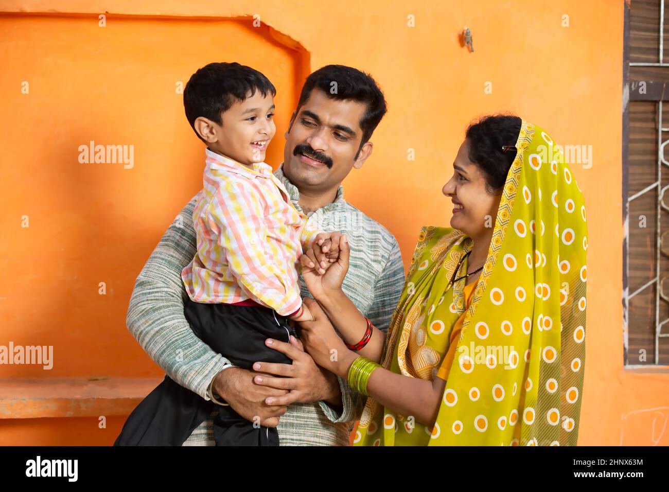 Happy young rural indian family laughing. father holding little child ...