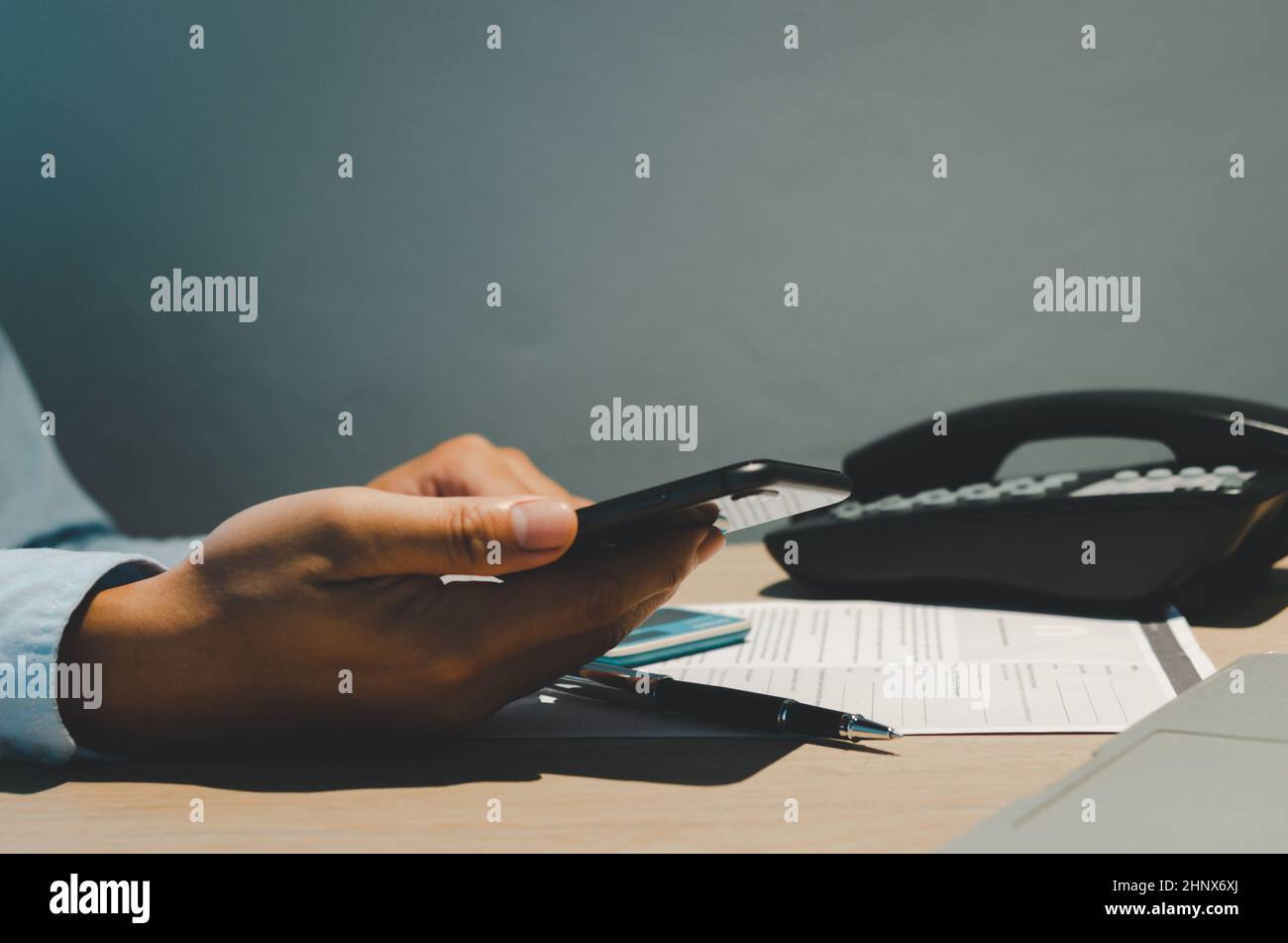 hand holding smart phone on desk with document paper work and phone at ...