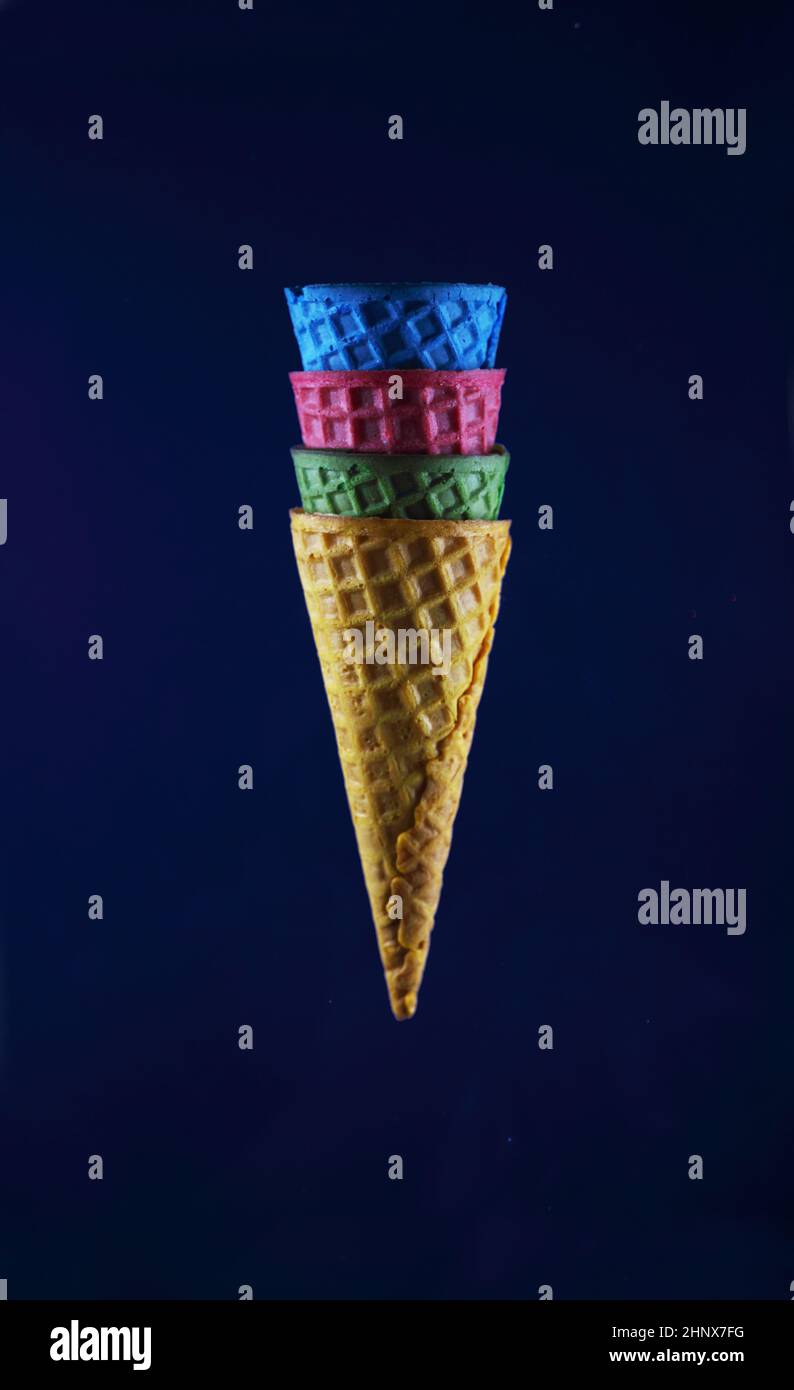 a pile of four waffle cones of different colours isolated against blue ...