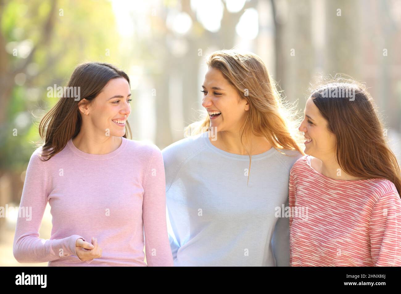 Three happy friends talking and laughing walking in the street Stock ...