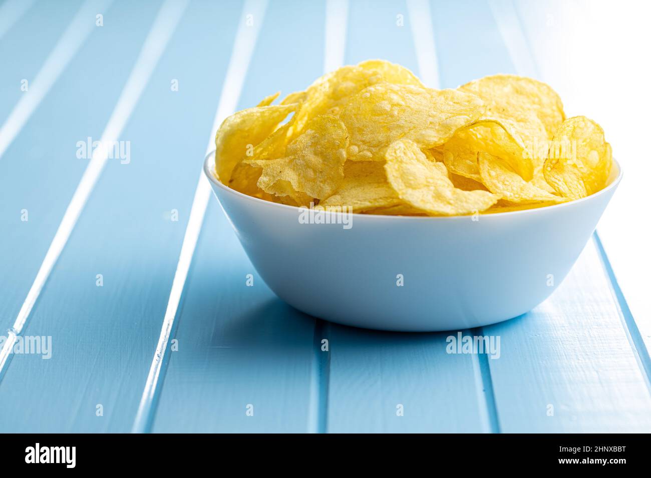 Crunchy potato chips. Potato crisps on blue table Stock Photo - Alamy