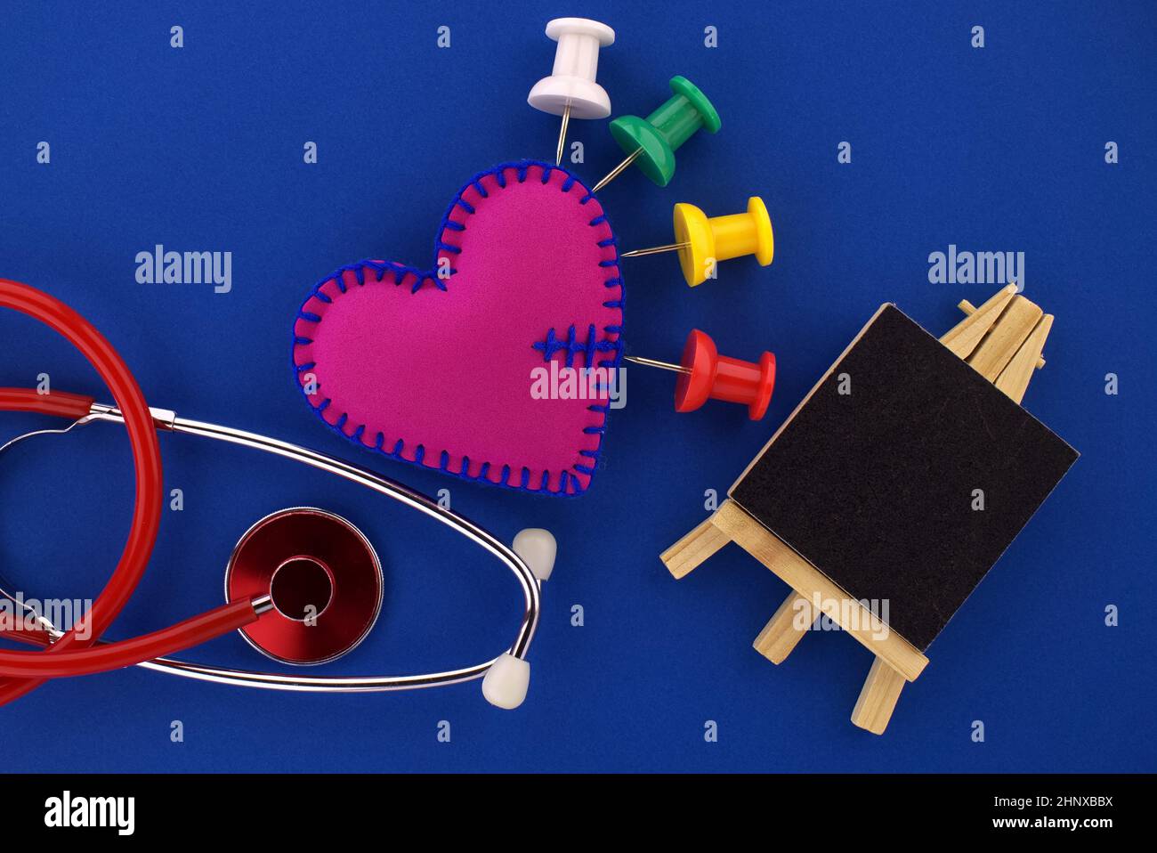 Medical concept with thumb tacks stuck into a felt heart symbolizing ...