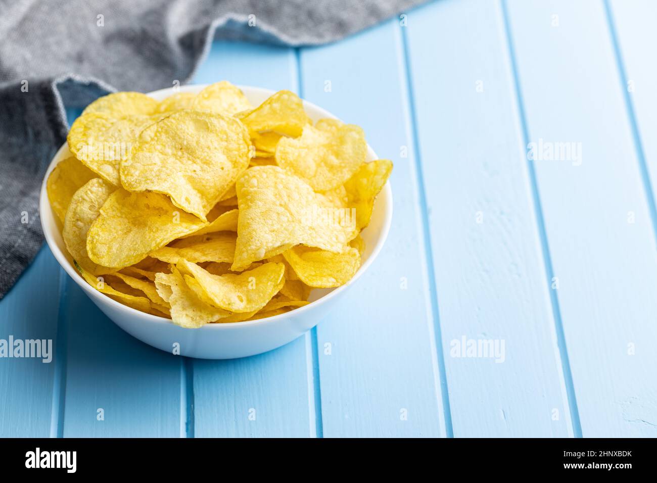 Crunchy potato chips. Potato crisps on blue table Stock Photo - Alamy