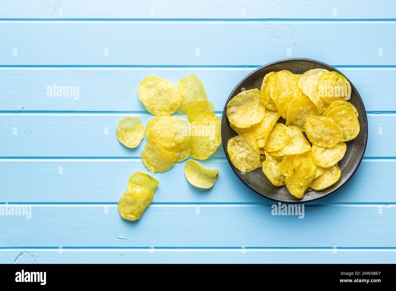 Crunchy potato chips. Potato crisps on blue table. Top view Stock Photo ...