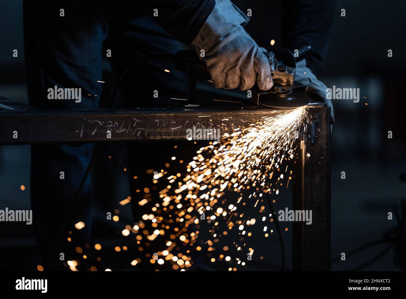 Man working on iron with grinder. Man at work. Sparkles and fire from ...