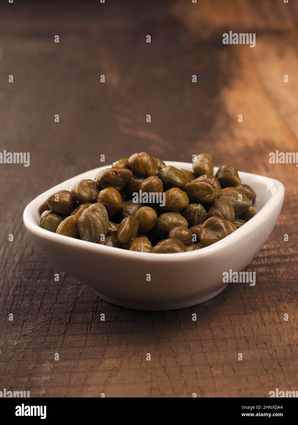 Organic capers in a white bowl on a rustic kitchen table, healthy food ...