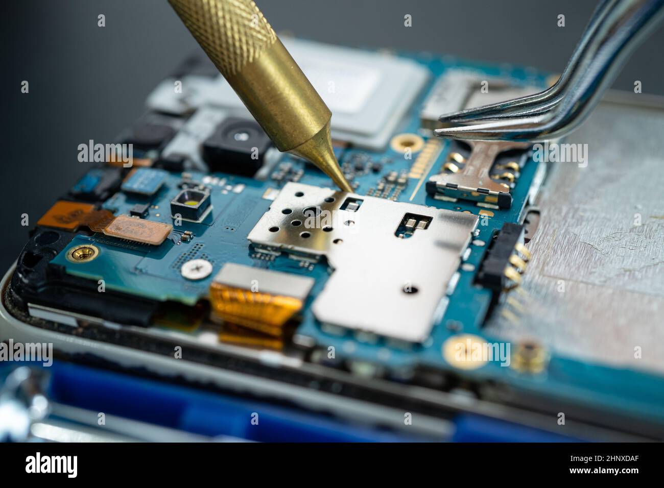 Technician repairing inside of mobile phone by soldering iron ...