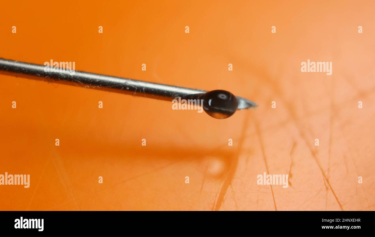 Close-up of vaccine drop on syringe needle. Water drop falling from the ...