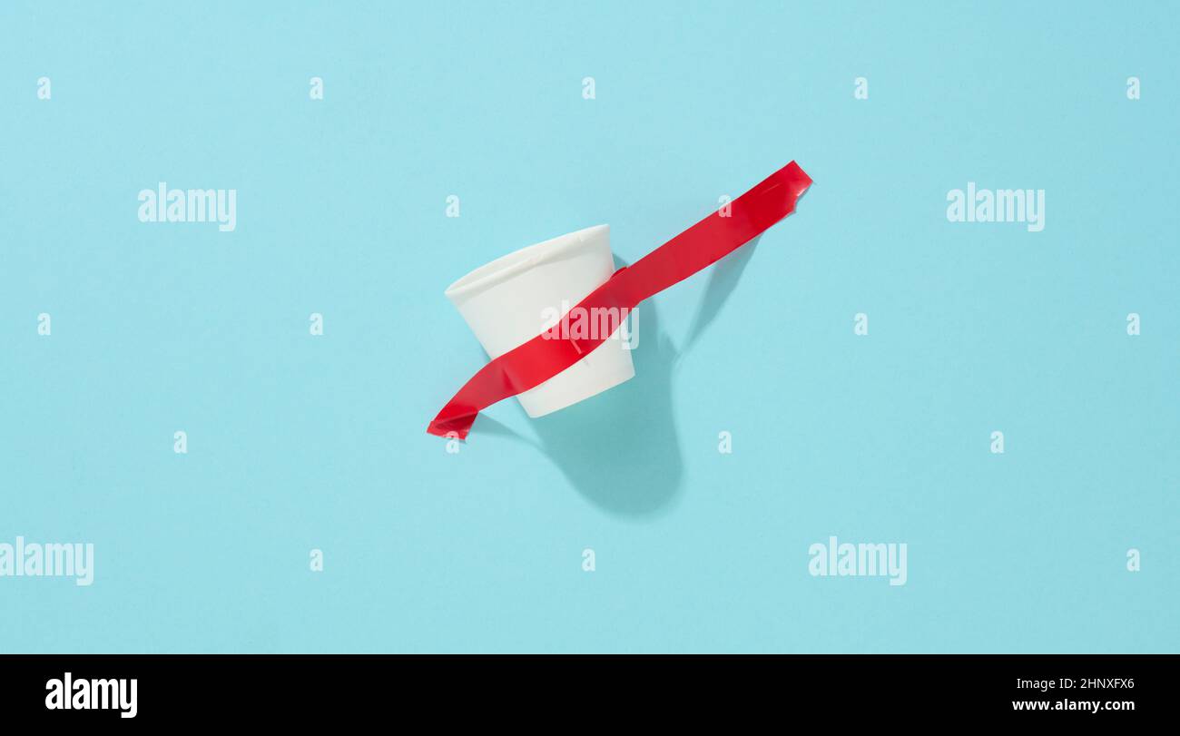 white cardboard cup glued with red sticky tape to the blue background ...