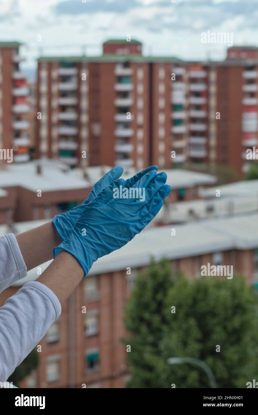 gloved hands clapping from a balcony with the city in the background ...