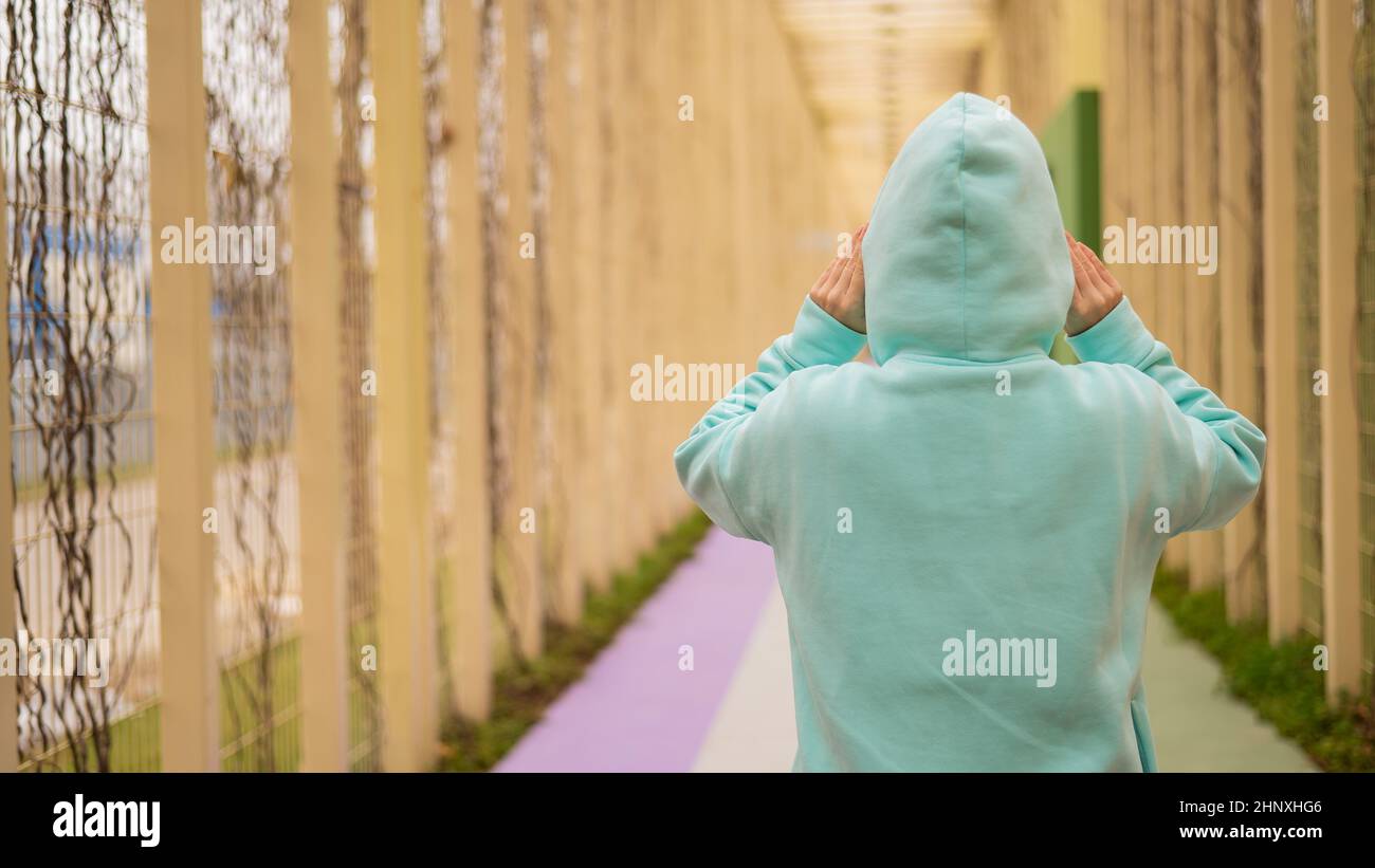 Caucasian Red Haired Woman Puts On The Hood Of A Mint Hoodie And Walks