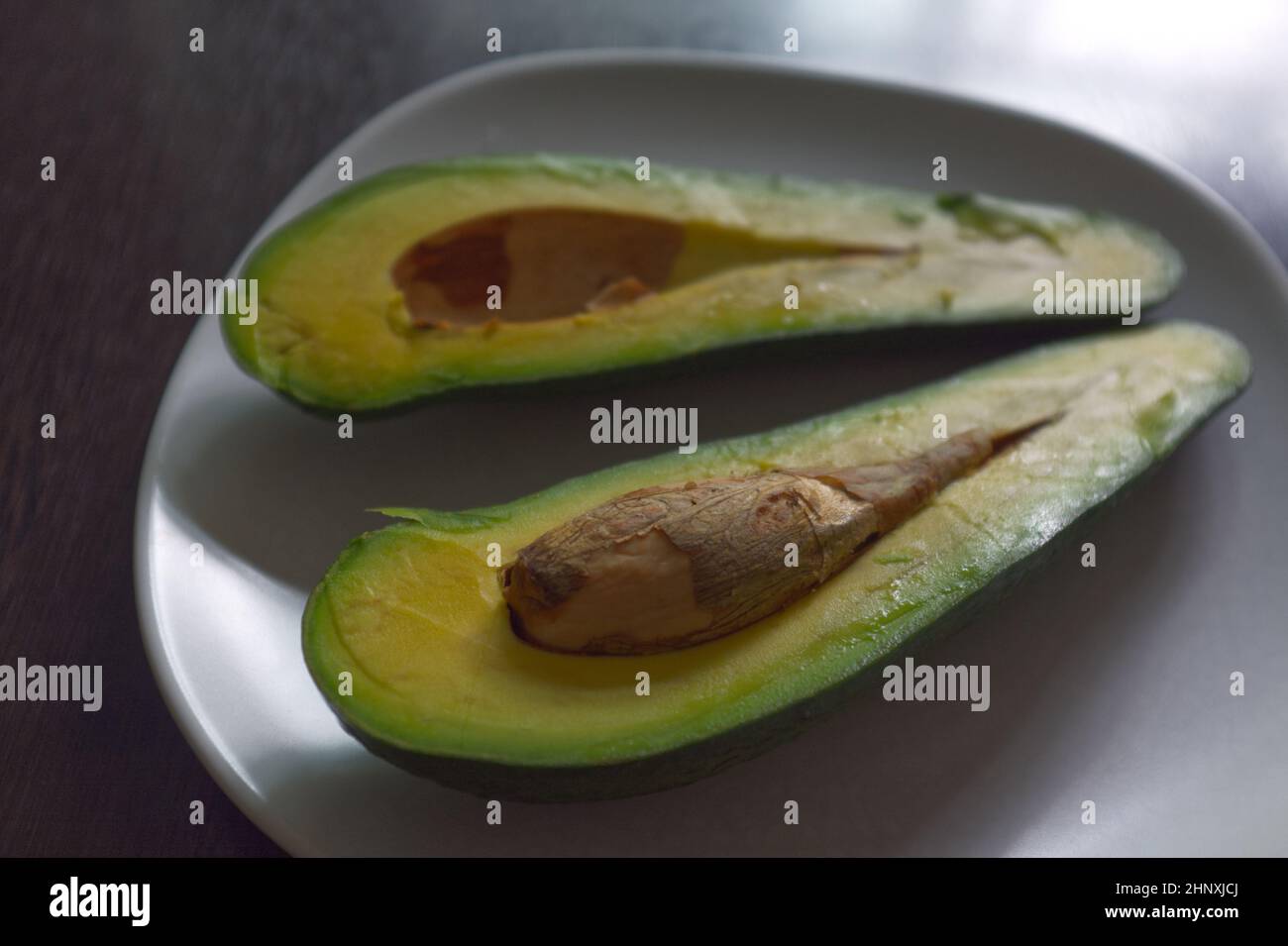 Avocado split in half, isolated on a black background Stock Photo - Alamy
