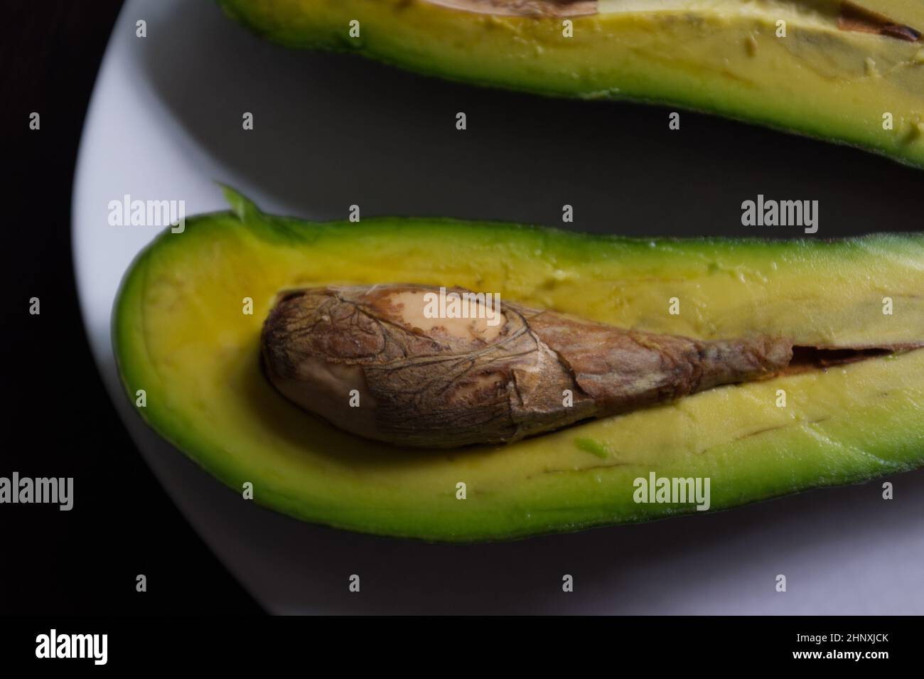 Avocado split in half, isolated on a black background Stock Photo - Alamy