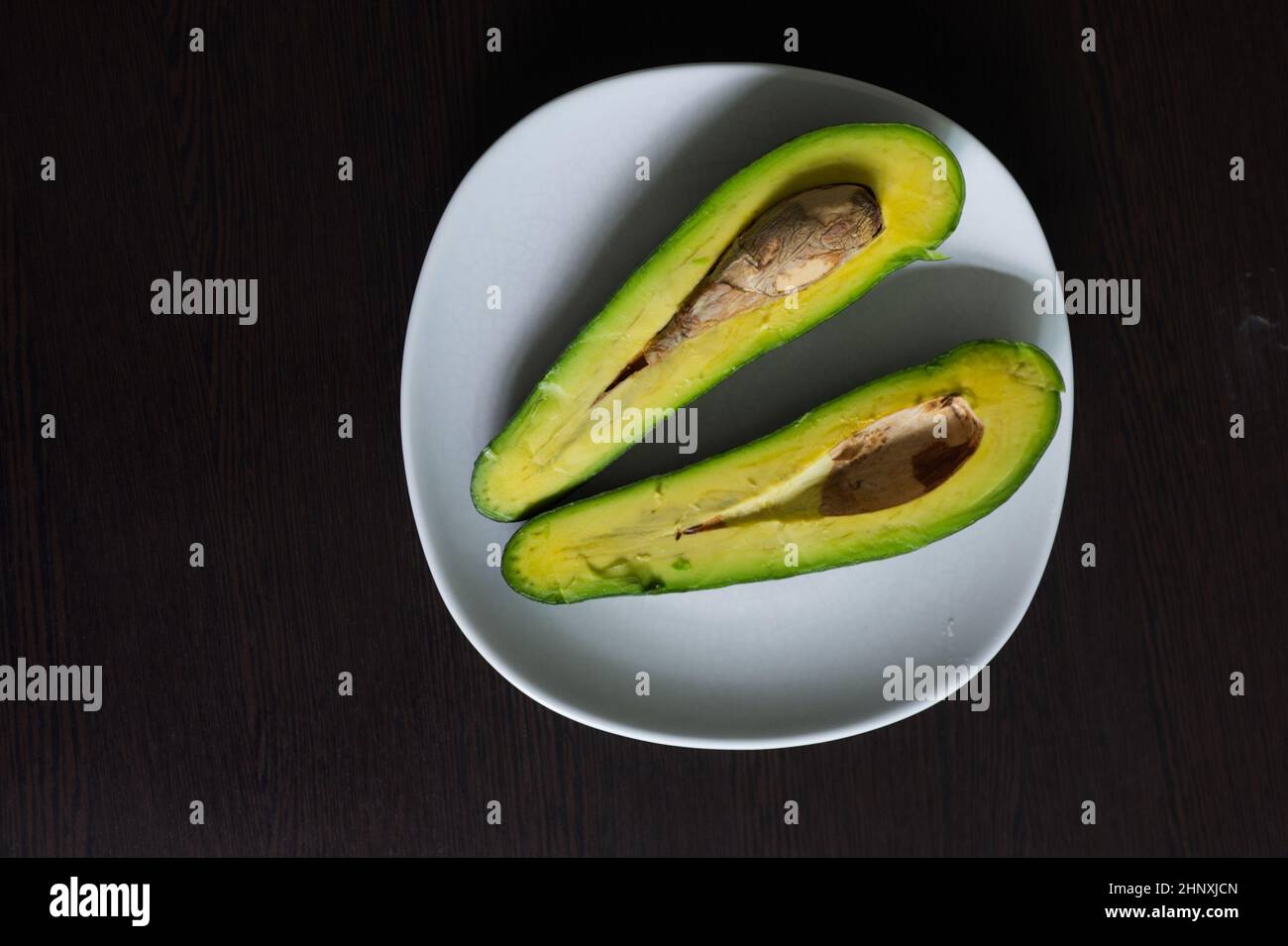 Avocado split in half, isolated on a black background Stock Photo - Alamy