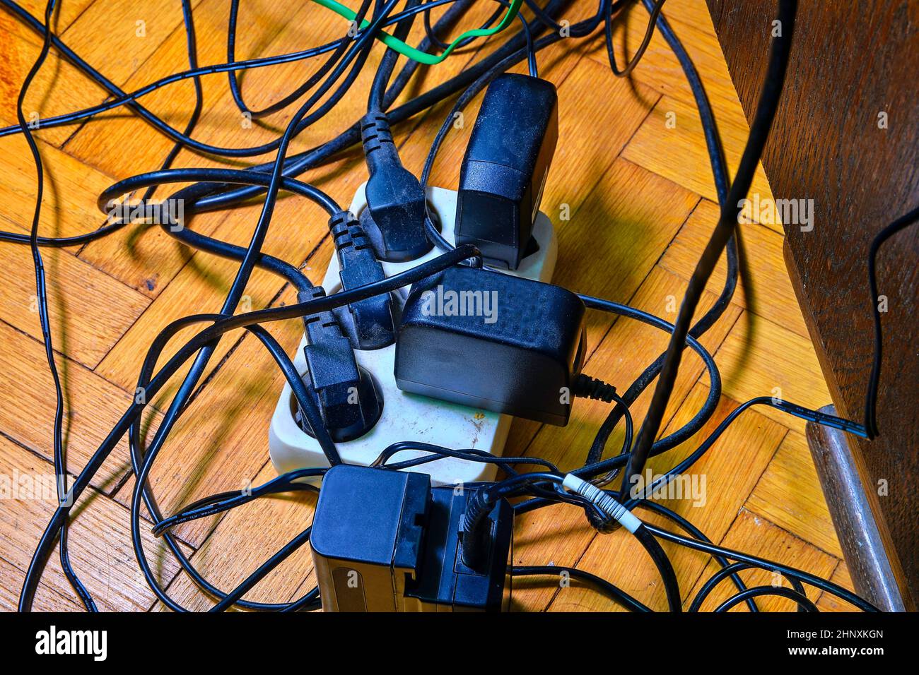 Tangled wires and battery charges on parquete floor. Domestic ...