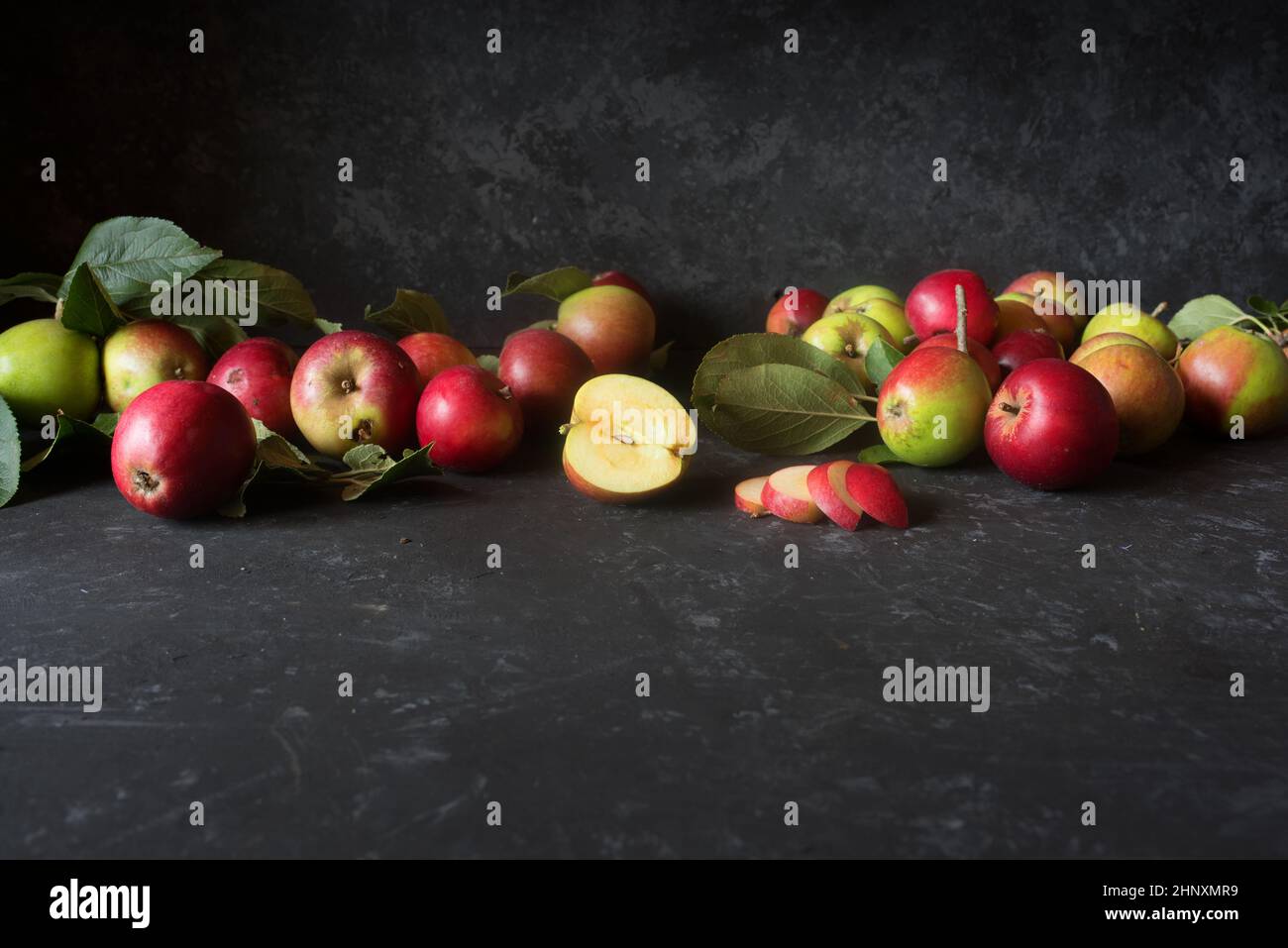 Healthy seasonal red and green fruits with leaves on dark background ...