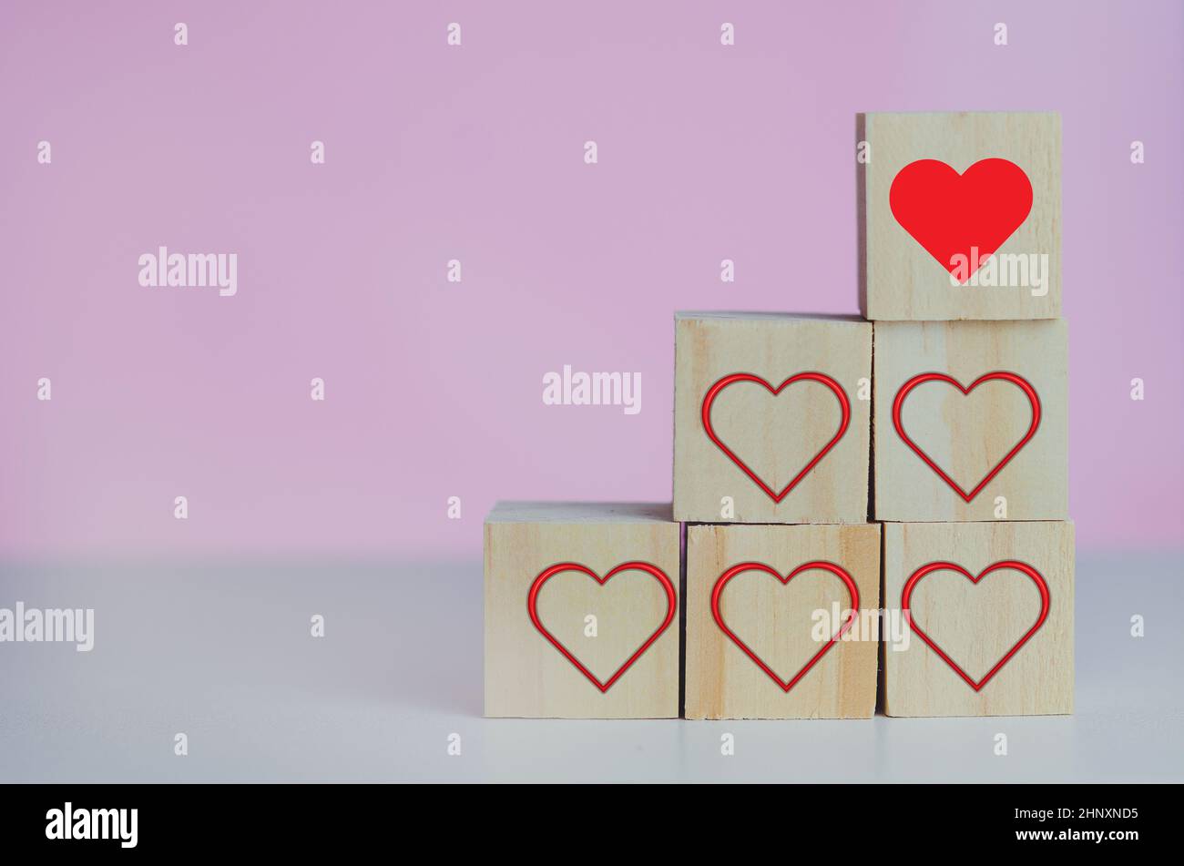 Wooden cubes with love symbol heart red on the pink background and copy ...