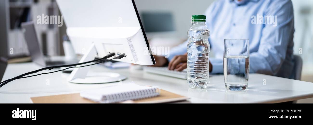 Water Bottle And Drinking Glass On Desk And Man Using Computer Stock ...