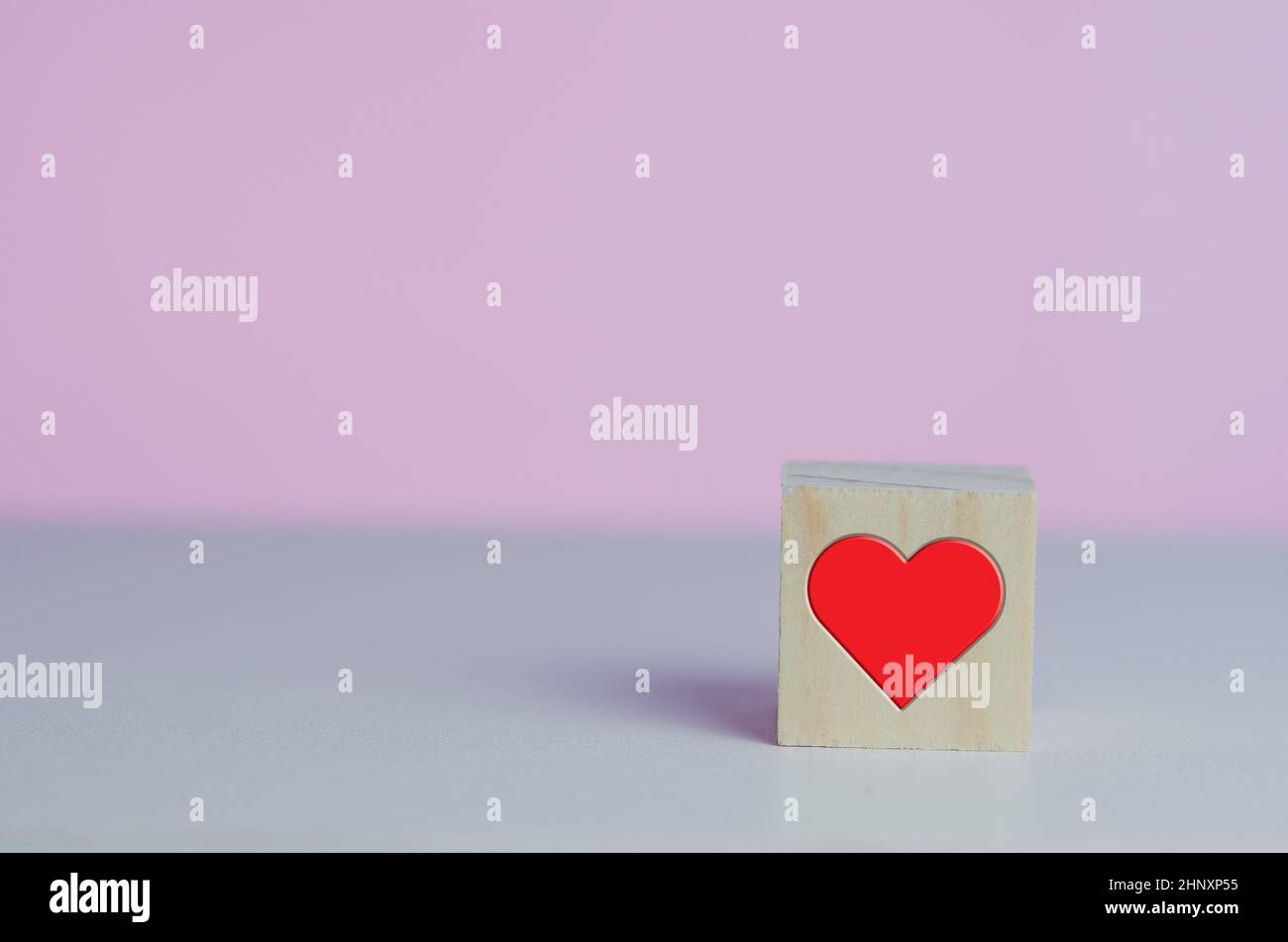 Wooden cubes with love symbol heart red on the pink background and copy ...