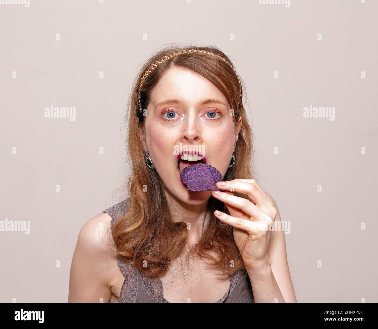 Young beautiful woman eating purple vegetable chips Stock Photo - Alamy