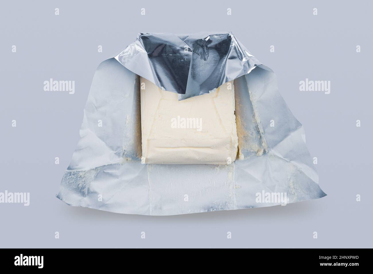 top view closeup of opened fresh piece of butter in silver foil ...