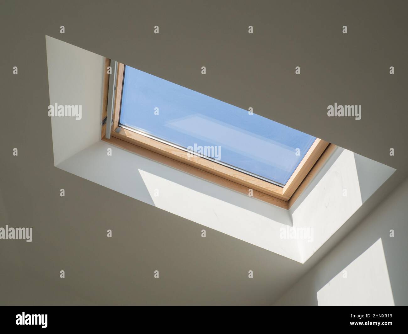 dormer wooden window in the white sloping ceiling overlooking the blue ...