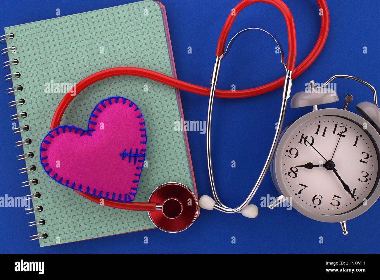 Medical concept with stethoscope and red heart, alarm clock and open ...