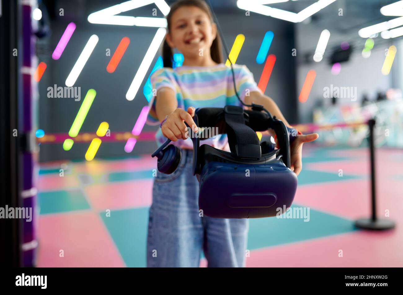 Cheerful little girl holds virtual reality glasses. Kid playing 3d ...