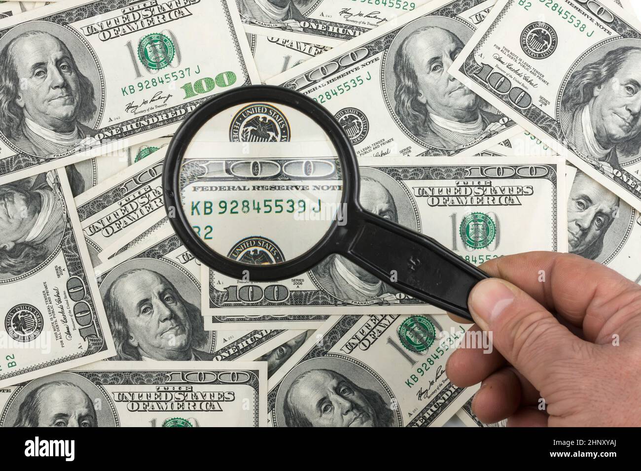 Hand with magnifying glass on a background of money .Concept Stock ...