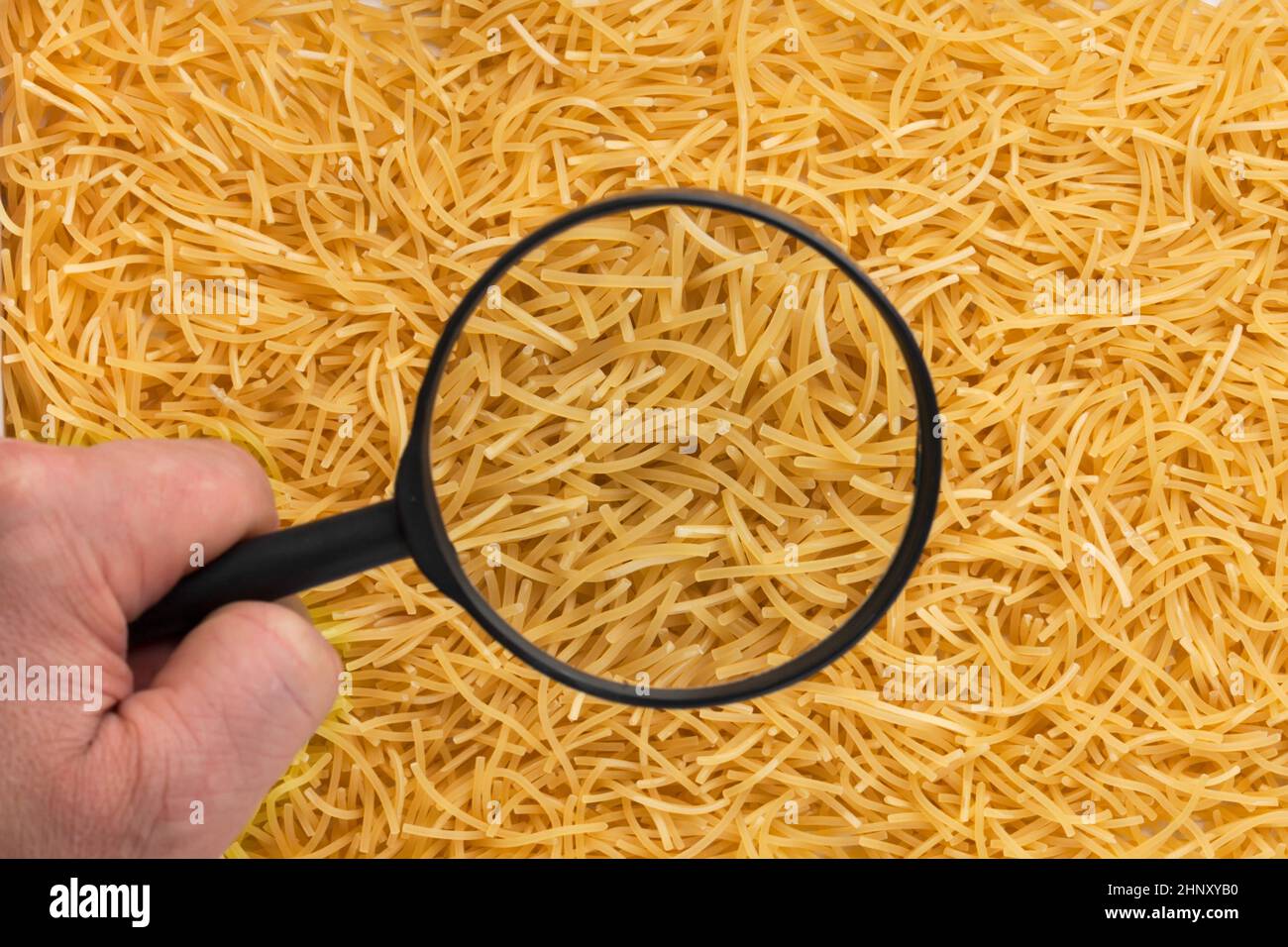 Human hand holding a magnifying glass over the pasta can be used as ...