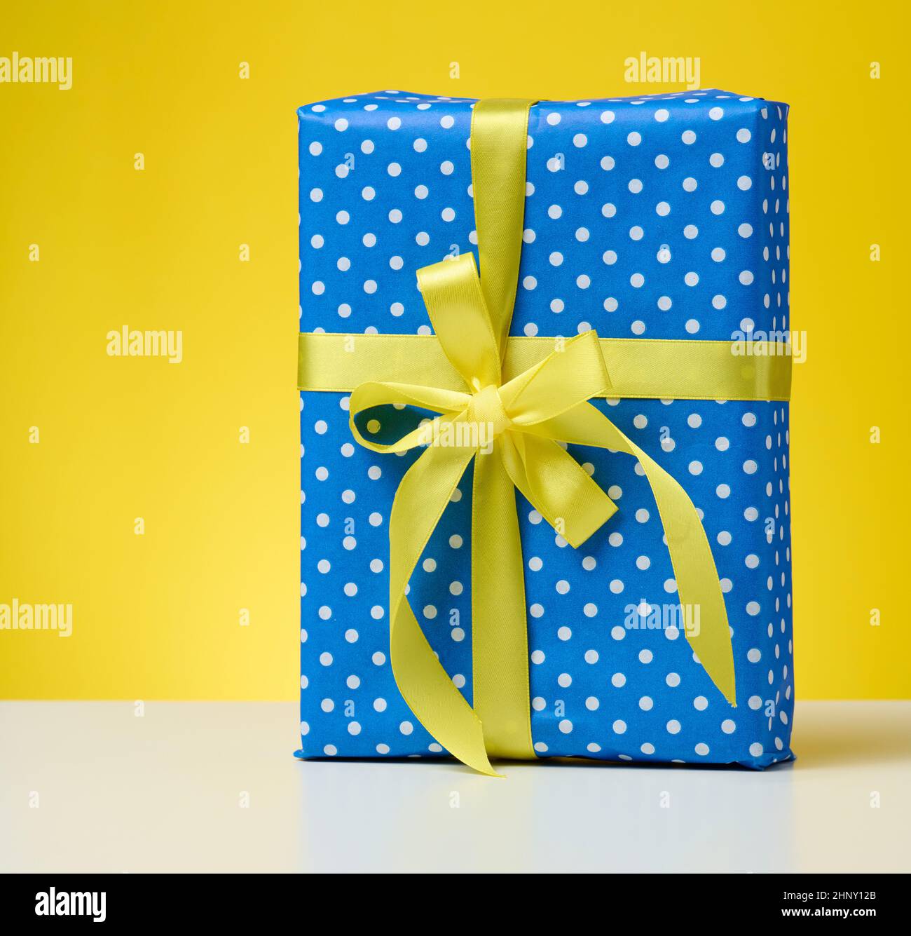box packed in festive blue paper and tied with silk yellow ribbon on a ...