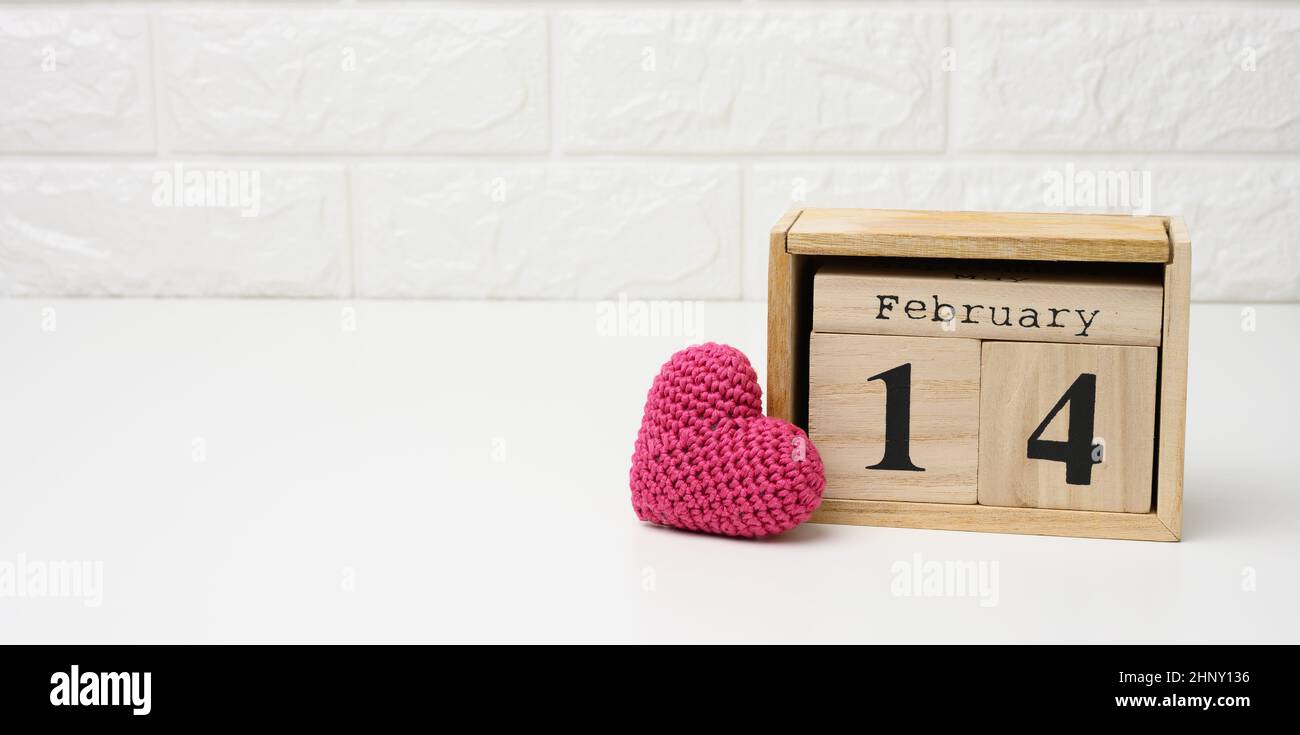 wooden calendar with date February 14 and red knitted heart, white ...