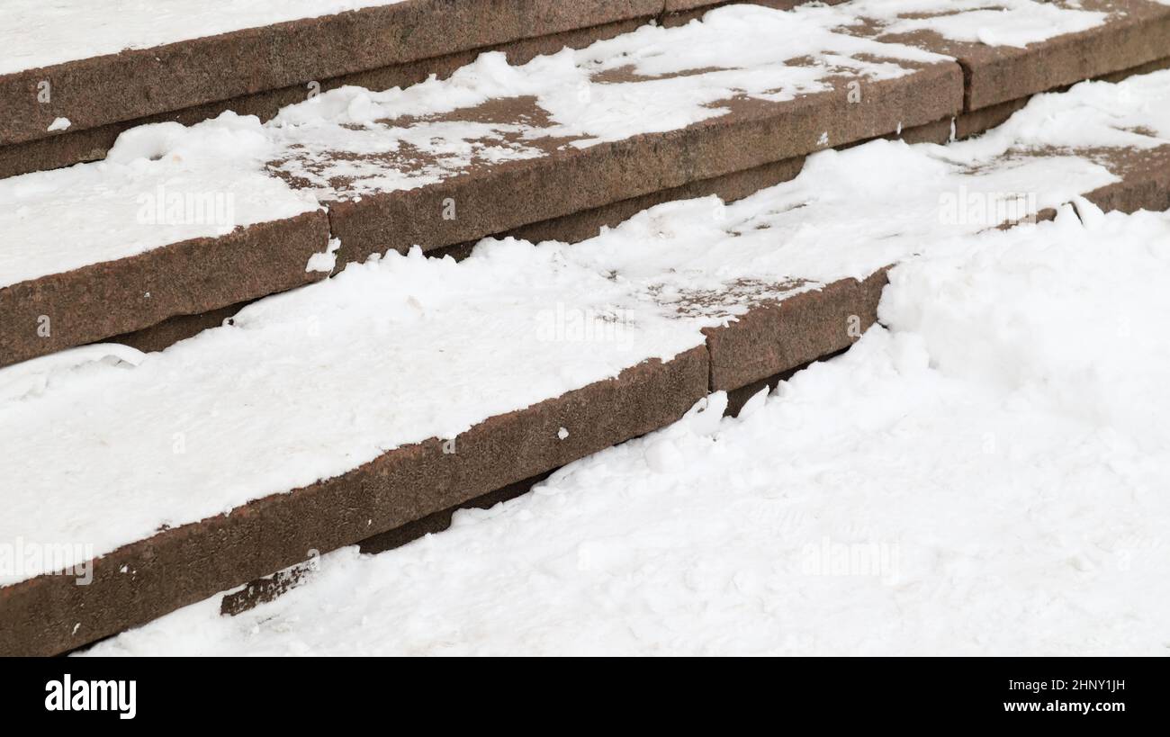 Snow covered slippery concrete stairs. First snow on granite stone ...