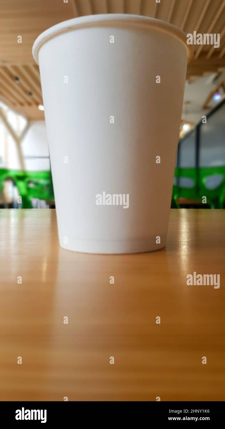 Paper white coffee cup disposable to take or go, on the wooden table of ...