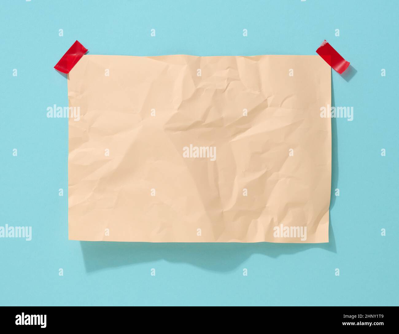 blank rectangular crumpled beige sheet of paper glued on a light blue ...